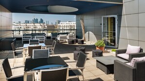 Terraço no telhado com área de estar ao ar livre, vista para o horizonte urbano e uma área coberta com porta.