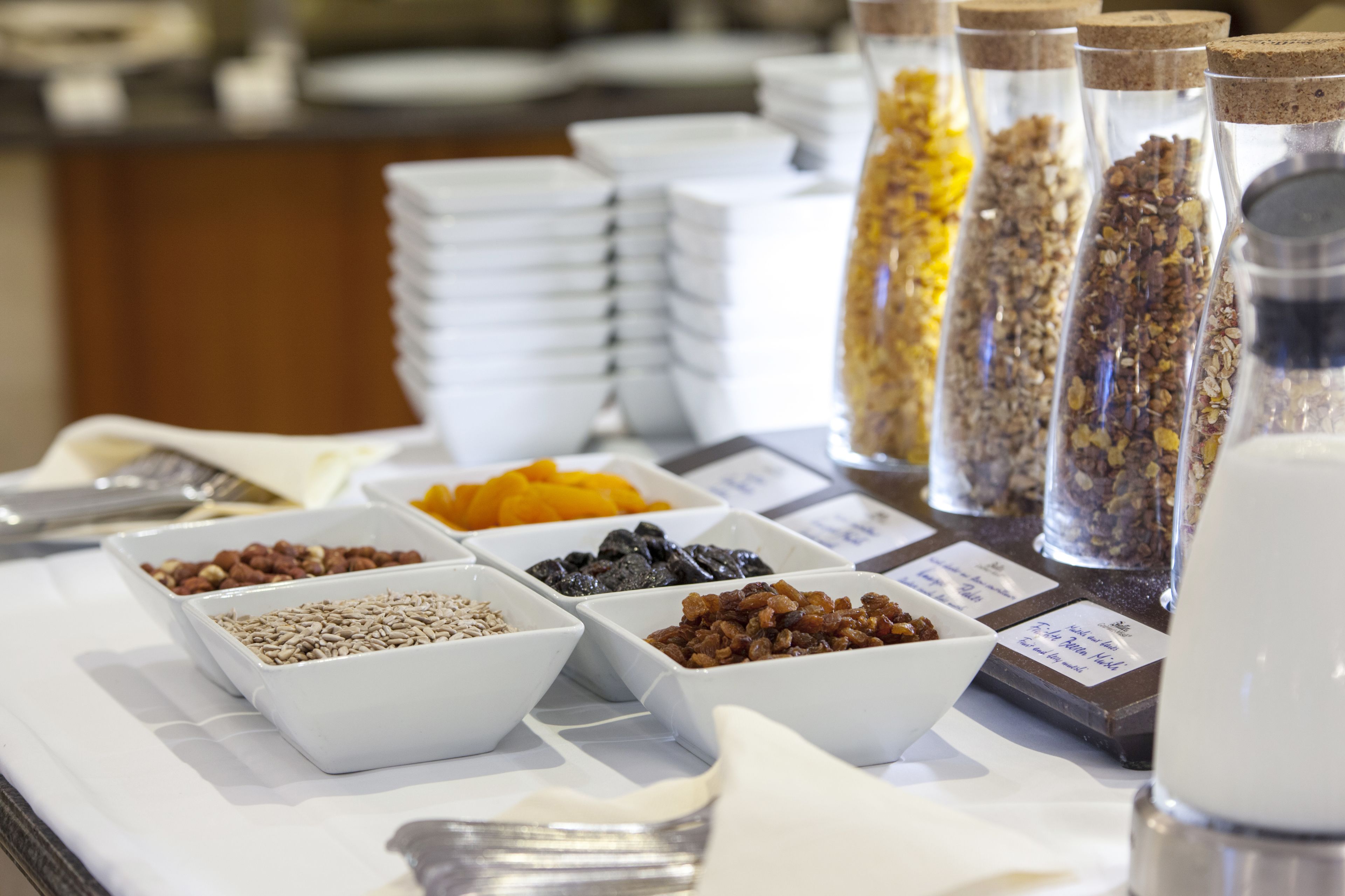 Buffet com diversos alimentos em tigelas e potes, incluindo nozes, frutas secas e grãos.