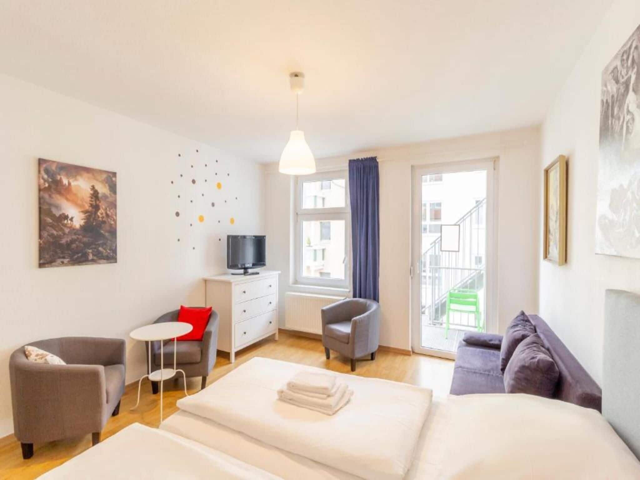 Quarto de hotel moderno com cama, escrivaninha, cadeira, televisão e varanda com vista para edifícios.