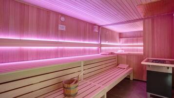 Uma sauna com bancos de madeira e iluminação rosa.