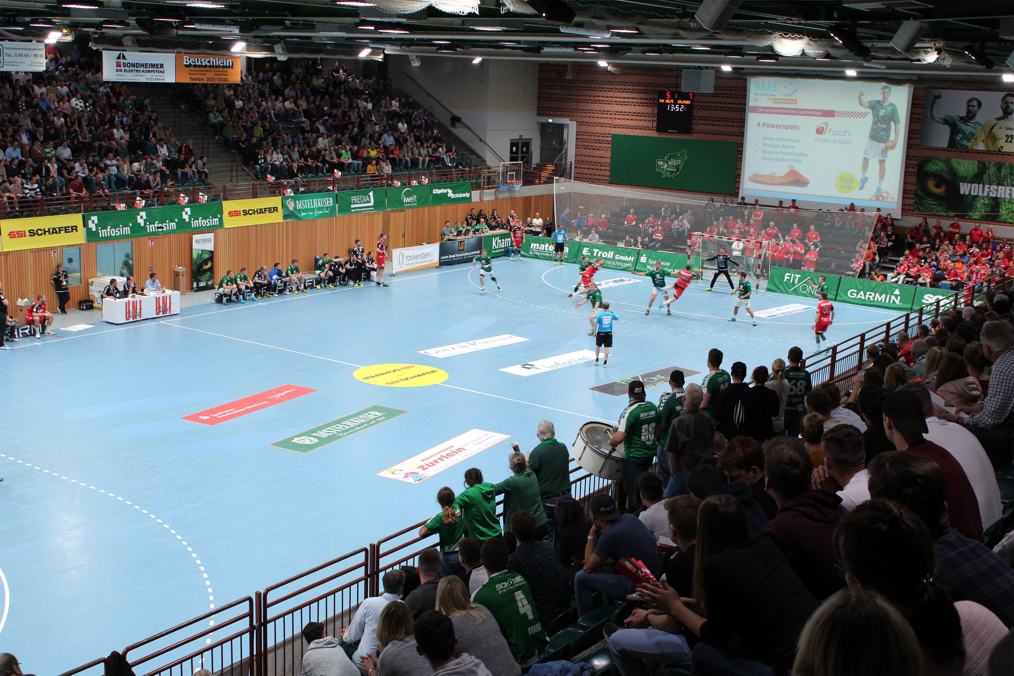 Uma arena esportiva coberta com superfície de jogo azul, cercada por espectadores.