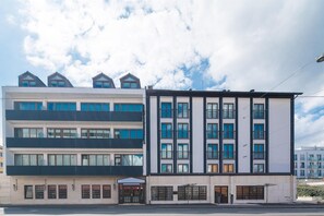 Um edifício de vários andares com telhado plano, grandes janelas e entrada com portão.