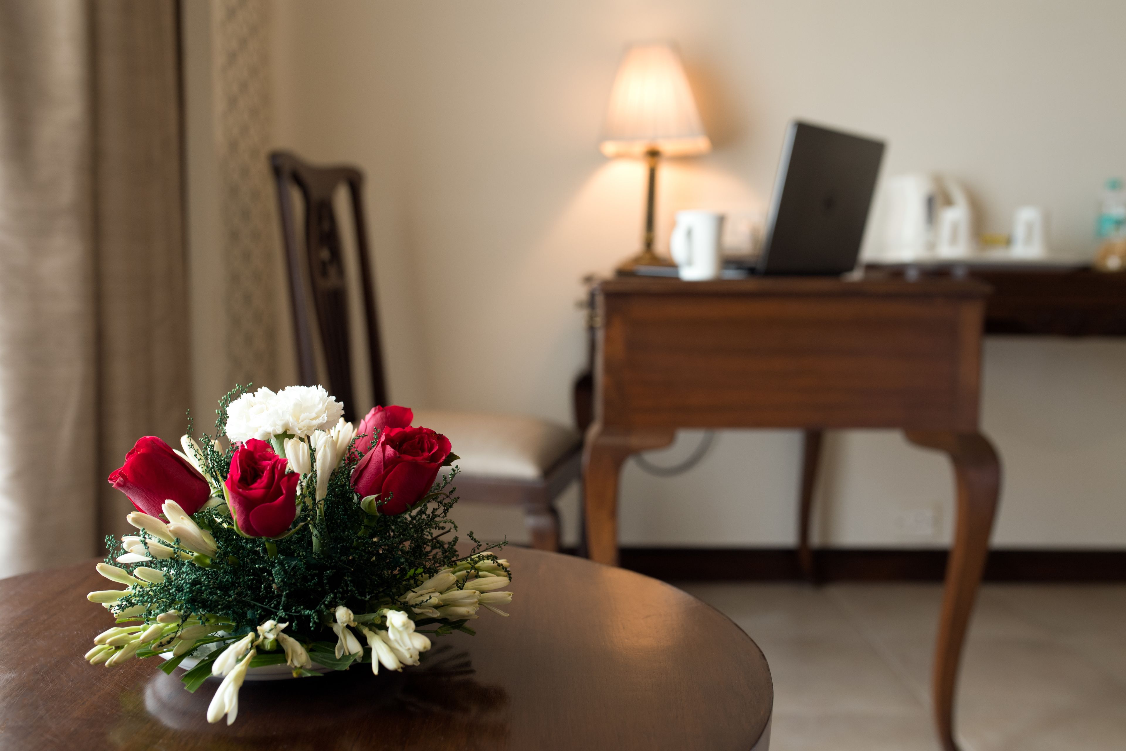 Um arranjo de flores vermelhas e brancas sobre uma mesa de madeira em um quarto de hotel.