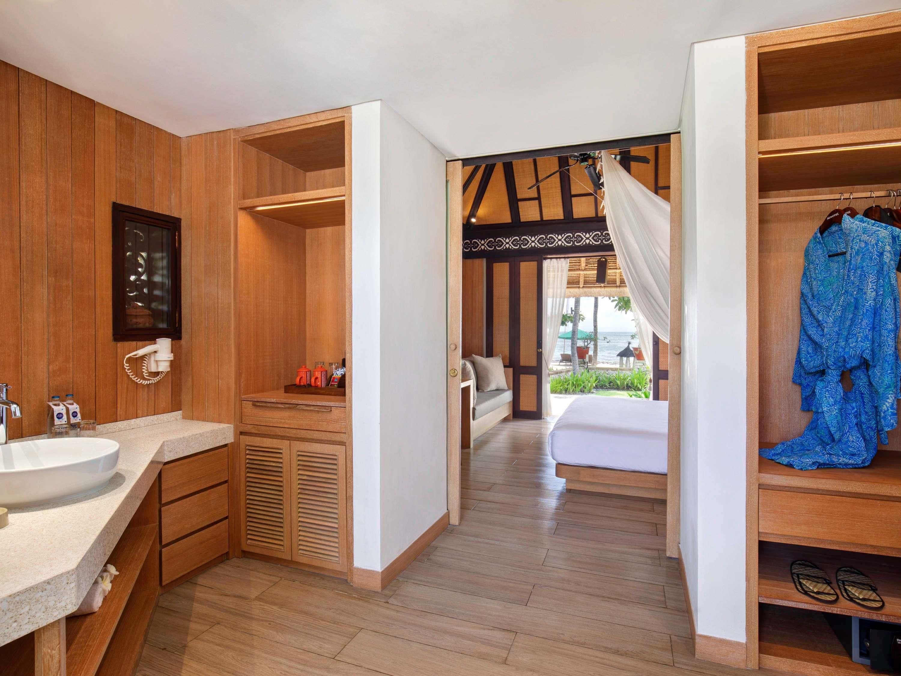 Uma casa de banho moderna com toucador de madeira, uma grande pia e zona de duche.