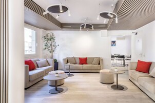 Uma sala de estar moderna com um sofá, duas mesas redondas e uma planta.