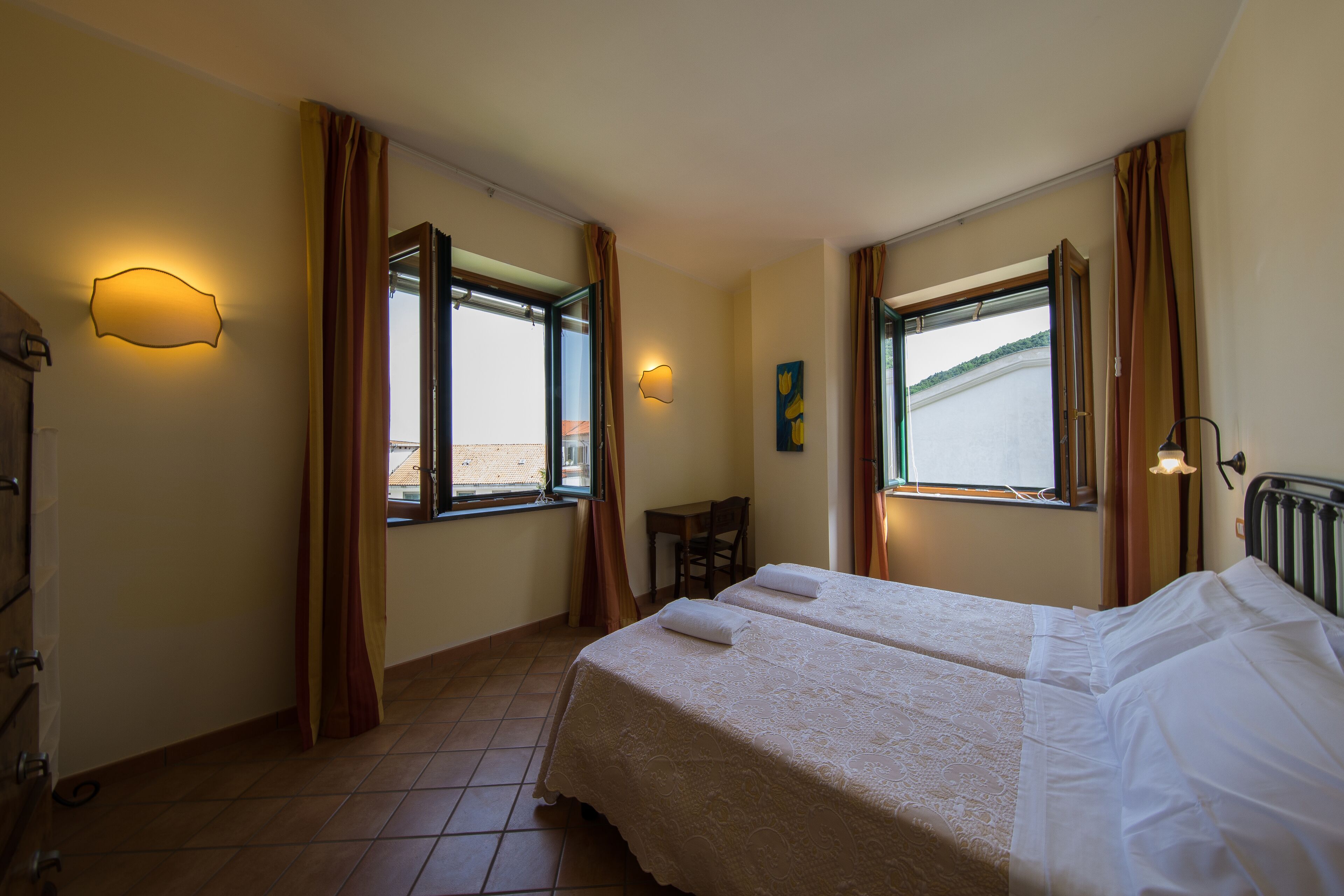 Quarto de hotel com duas camas, uma escrivaninha e uma cadeira.
