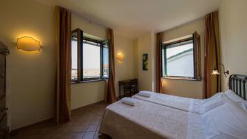 Quarto de hotel com duas camas, uma escrivaninha e uma cadeira.