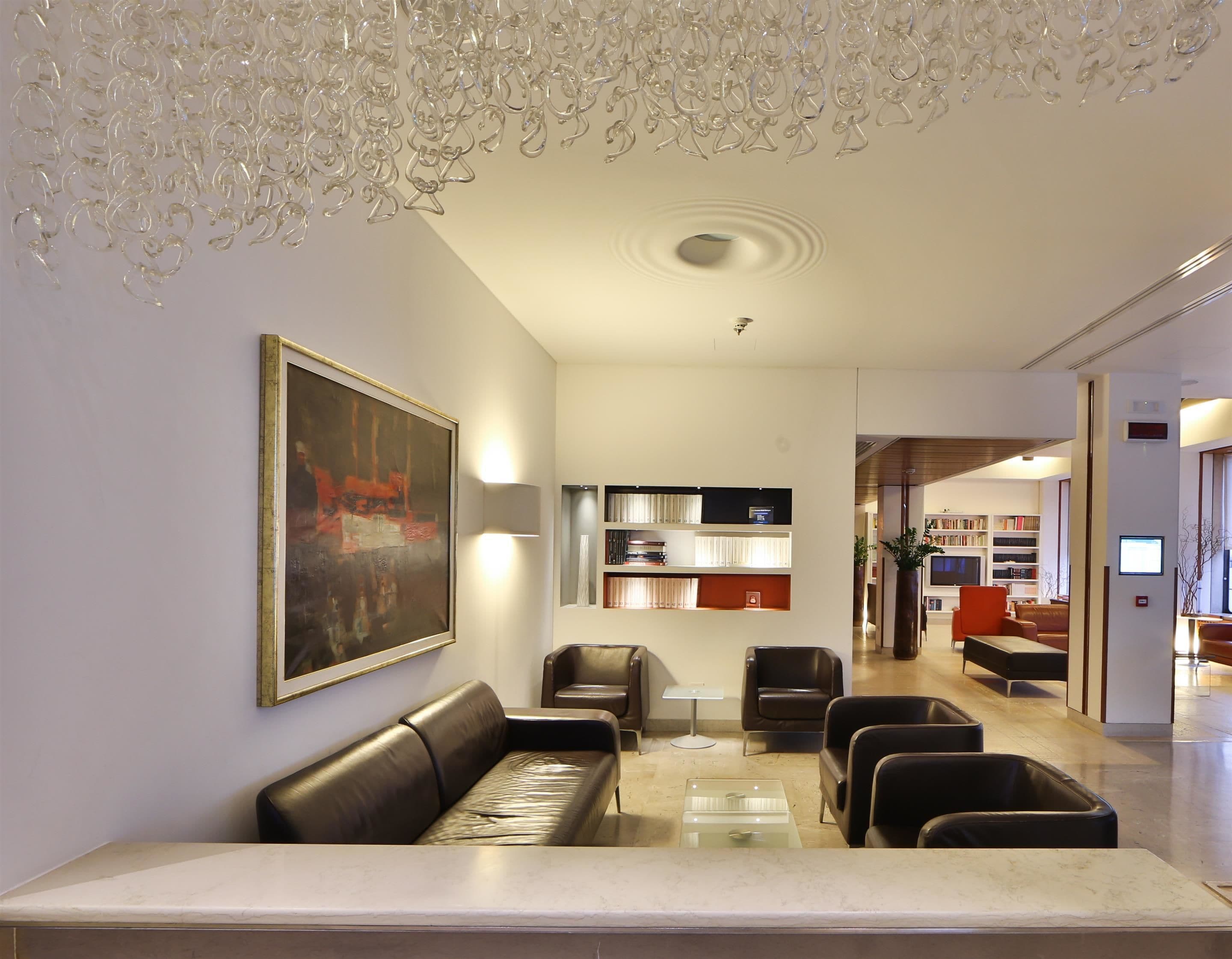 Uma sala de estar moderna com um sofá, poltronas, uma mesa de centro, uma estante e um quadro na parede.