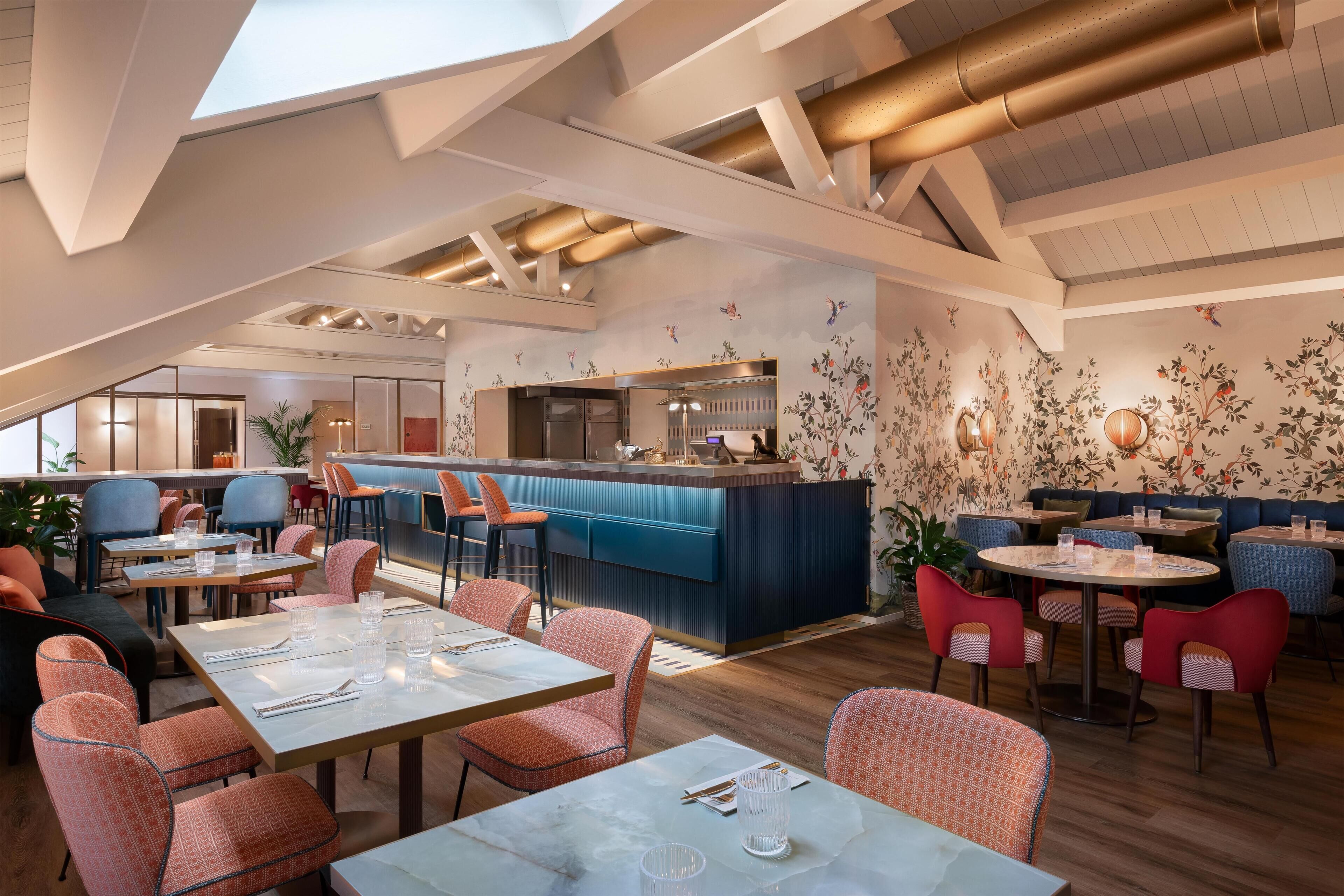 Restaurante com pé-direito alto, área de bar e diferentes opções de assentos.