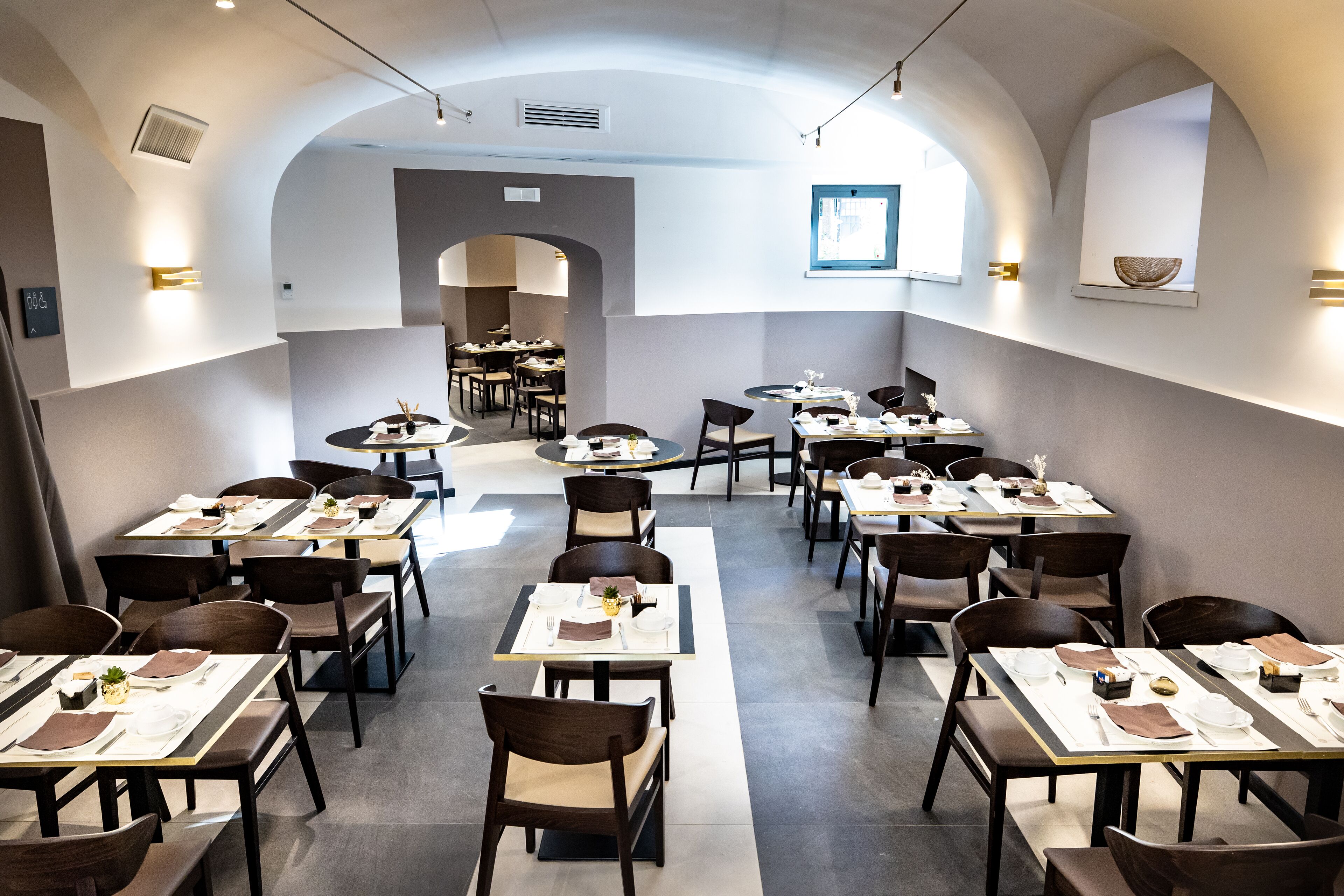 Restaurante com mesas preparadas para refeições, cadeiras e um corredor central.