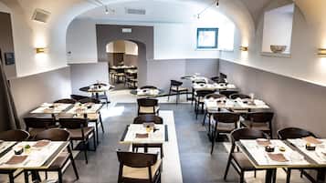 Restaurante com mesas preparadas para refeições, cadeiras e um corredor central.