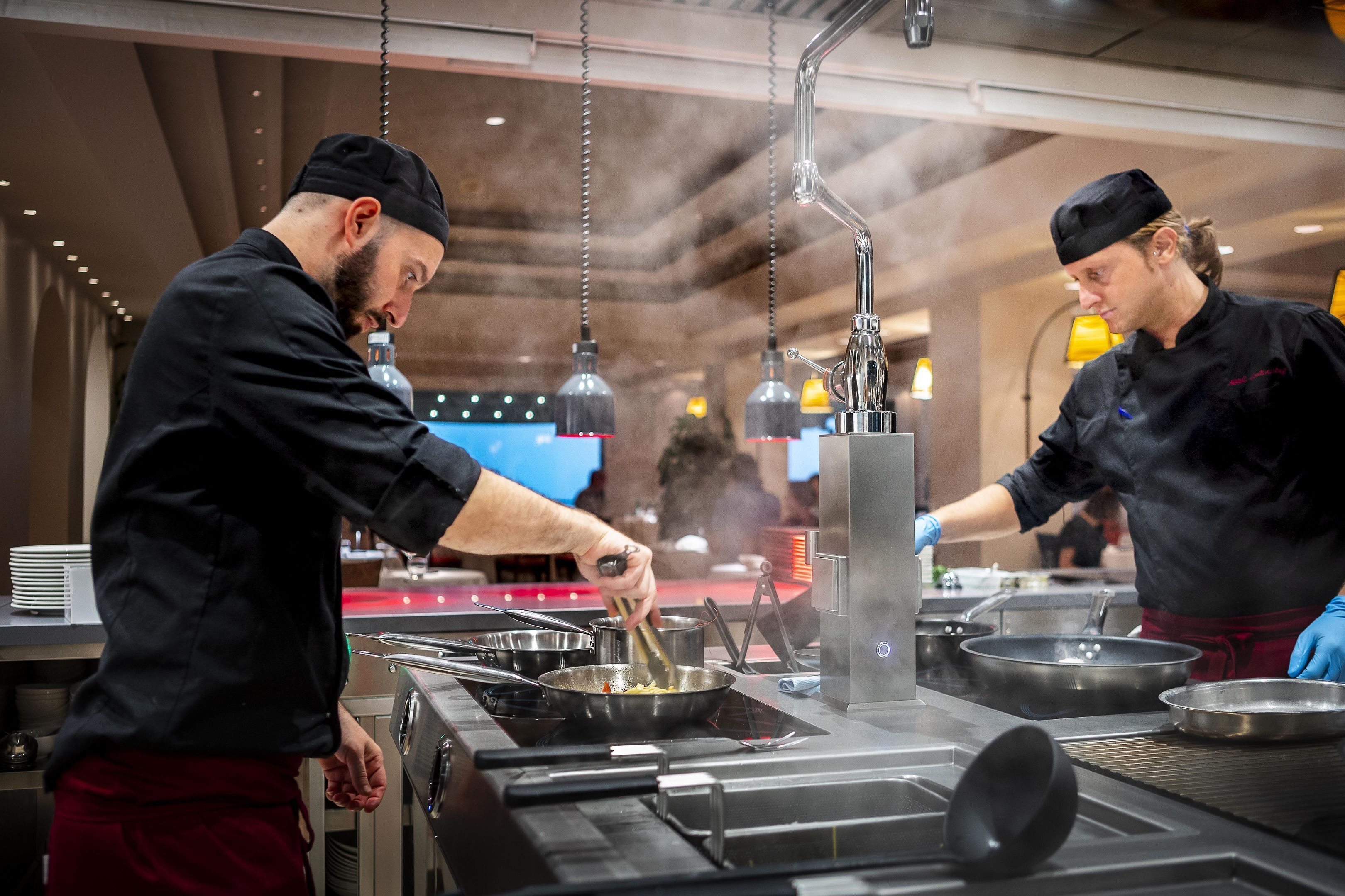 Uma cozinha profissional com chefs preparando alimentos.