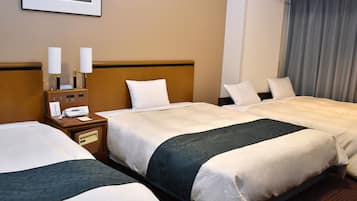 Quarto de hotel com duas camas, uma mesa de cabeceira com telefone e uma luminária na parede.
