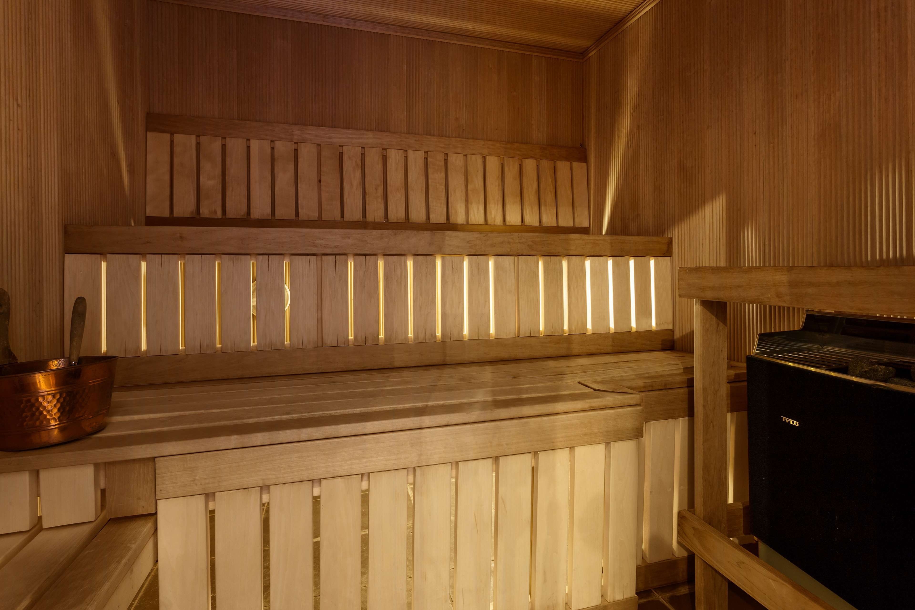 Uma sauna com bancos de madeira e aquecedor preto.