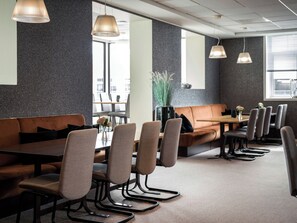 Uma sala de conferências moderna com uma mesa comprida, várias cadeiras, um sofá e iluminação pendente.