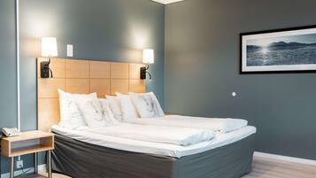 Quarto moderno com cabeceira de madeira, mesa de cabeceira com abajur e quadro na parede.