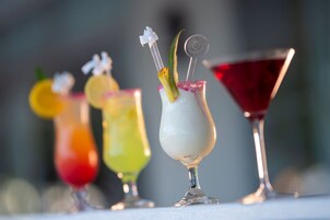 Diversos cocktails coloridos em diferentes copos, incluindo um copo martini e um copo highball.