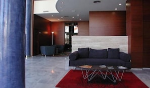 Um lobby moderno com um sofá escuro, um tapete vermelho e design minimalista.