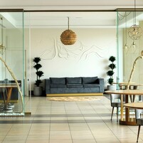 Uma sala de estar moderna com sofá, área de jantar com mesa e cadeiras, e parede decorativa com textura.
