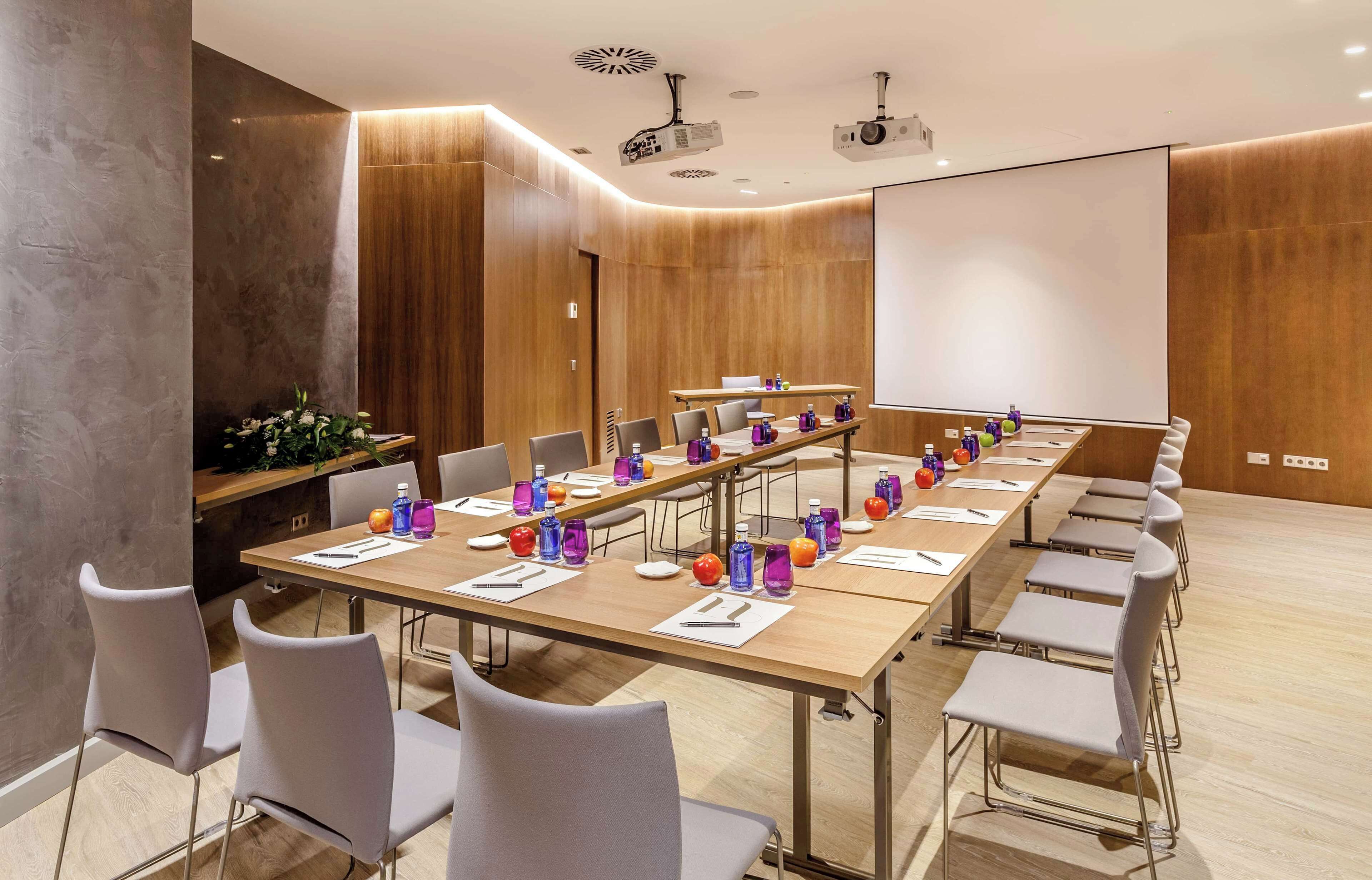 Uma sala de conferências com uma mesa comprida, cadeiras, um projetor e uma tela.