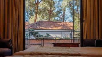 Quarto com uma janela grande, uma cama e duas cadeiras.