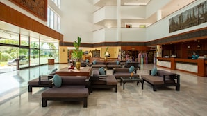 Um lobby amplo com várias áreas de estar, uma receção e grandes janelas com vista para o exterior.