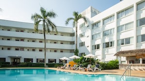 Um hotel com piscina, espreguiçadeiras e palmeiras.