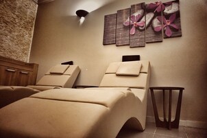 Sala de spa com duas cadeiras de massagem, uma obra de arte na parede e uma lixeira.