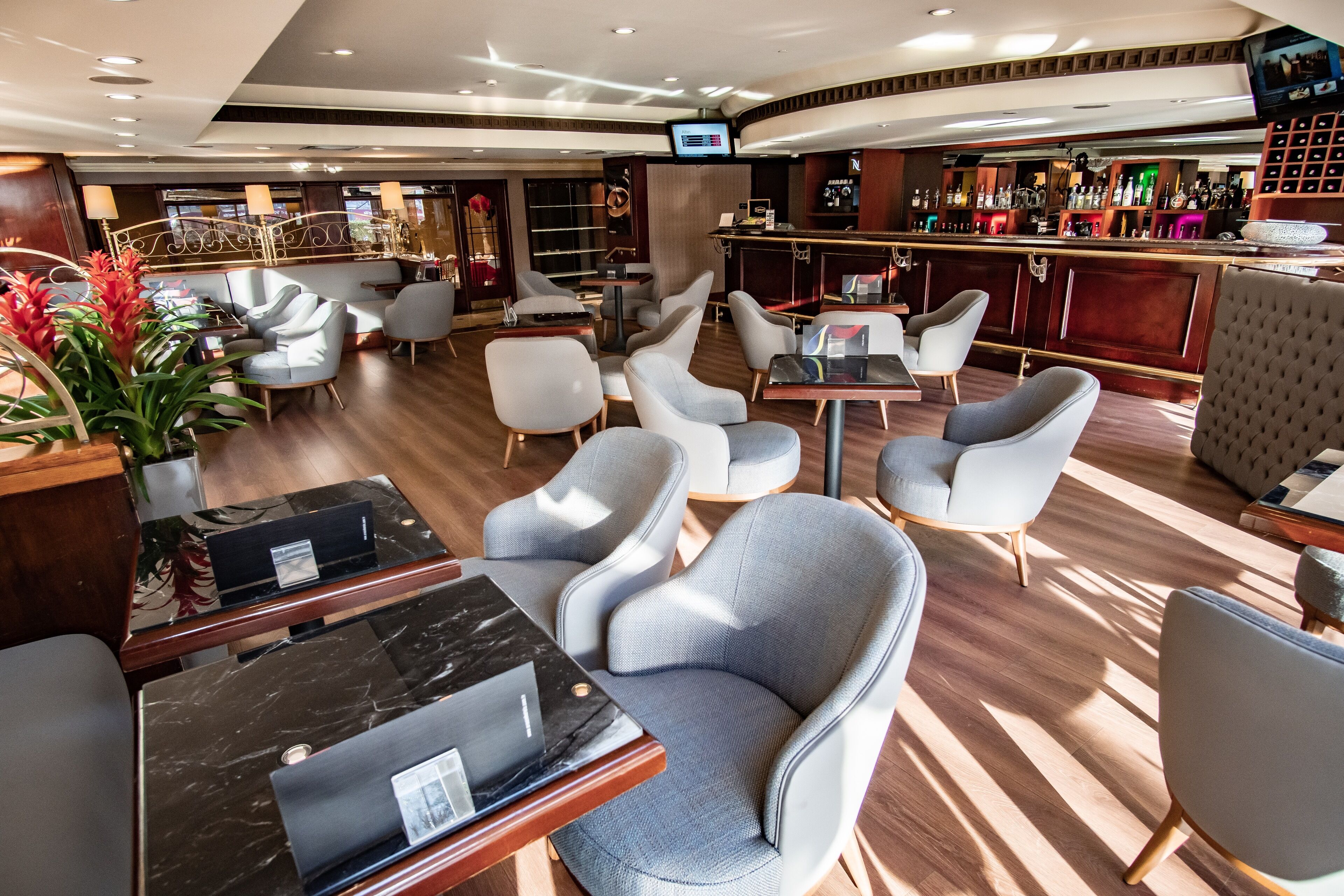 Uma área de bar moderna com assentos e uma tela de televisão.