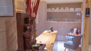 Uma área de bar com balcão longo, uma cadeira e prateleiras com toalhas e produtos de higiene pessoal.