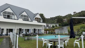 Um edifício branco grande com piscina, área de estar externa e vista para uma paisagem montanhosa.