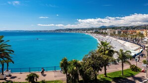Paisagem costeira com praia, calçadão e edifícios à beira-mar.