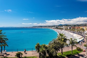 Paisagem costeira com praia, calçadão e edifícios à beira-mar.