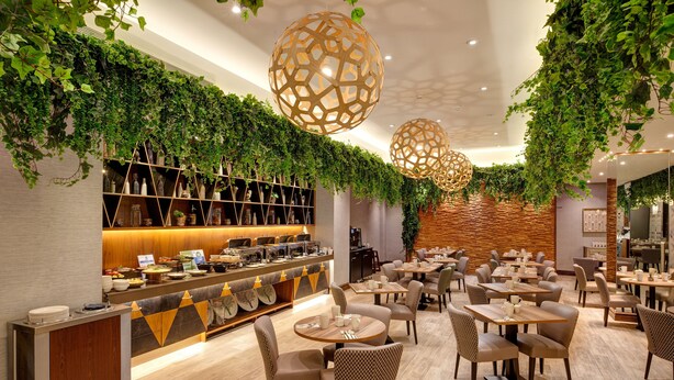 Um café moderno com balcão, área de estar e luminárias pendentes decorativas.