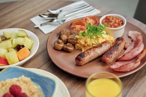 Prato de pequeno-almoço com enchidos, bacon, cogumelos, ovos mexidos e feijão.