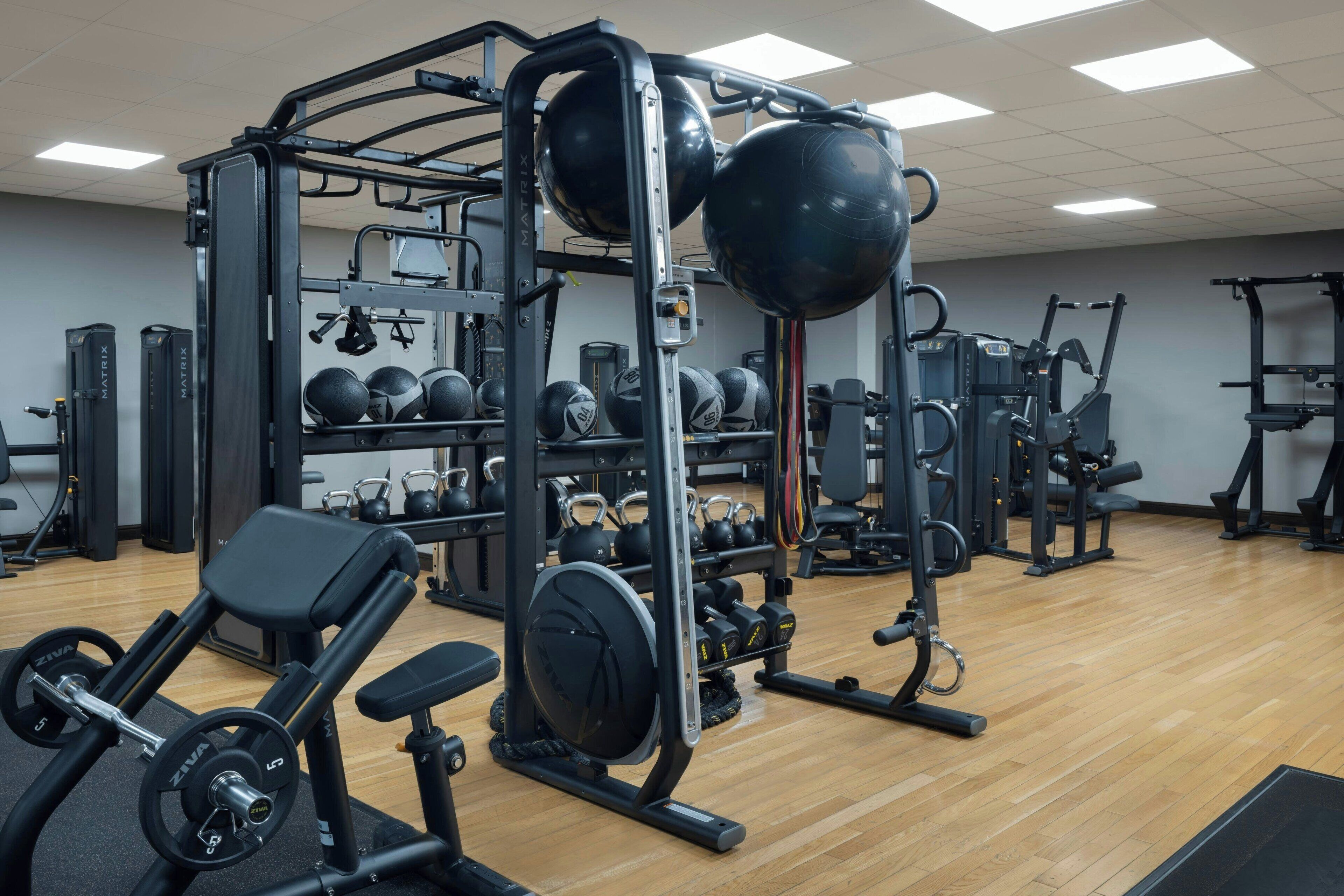 Uma academia com diversos equipamentos de exercício, incluindo máquinas de musculação, pesos livres e kettlebells.