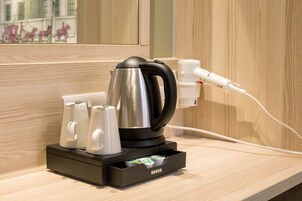 Uma cafeteira com quatro xícaras e uma tomada em uma bancada de madeira.
