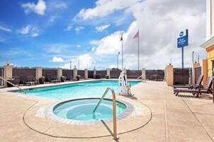 Piscina com espreguiçadeiras e banheira de hidromassagem, cercada por um espaço de terraço.