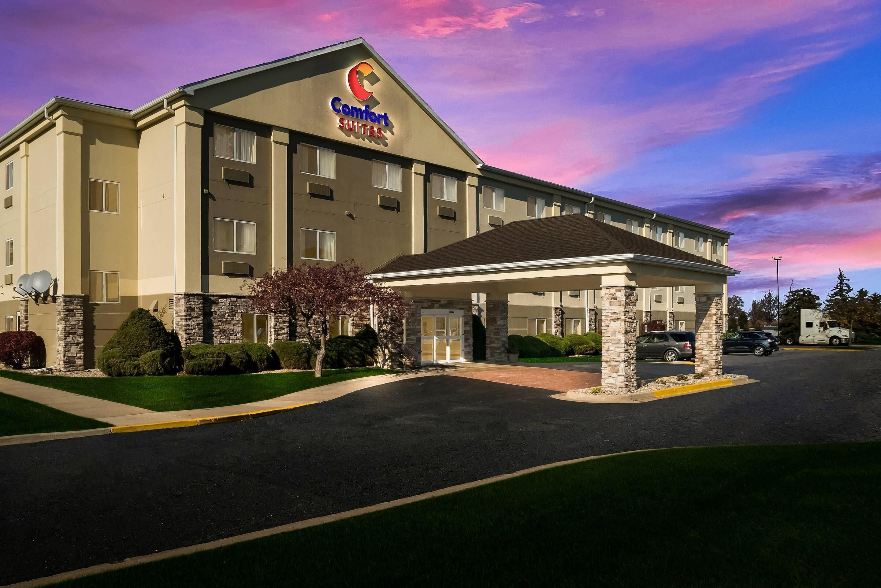 Um hotel Comfort Suites com entrada coberta, vários andares e estacionamento.