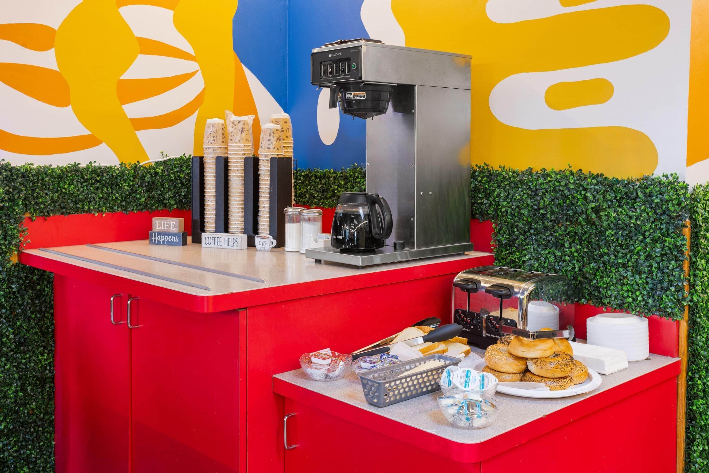 Uma estação de café com cafeteira, chávenas e pastelaria.