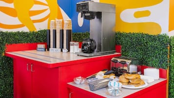 Uma estação de café com cafeteira, chávenas e pastelaria.