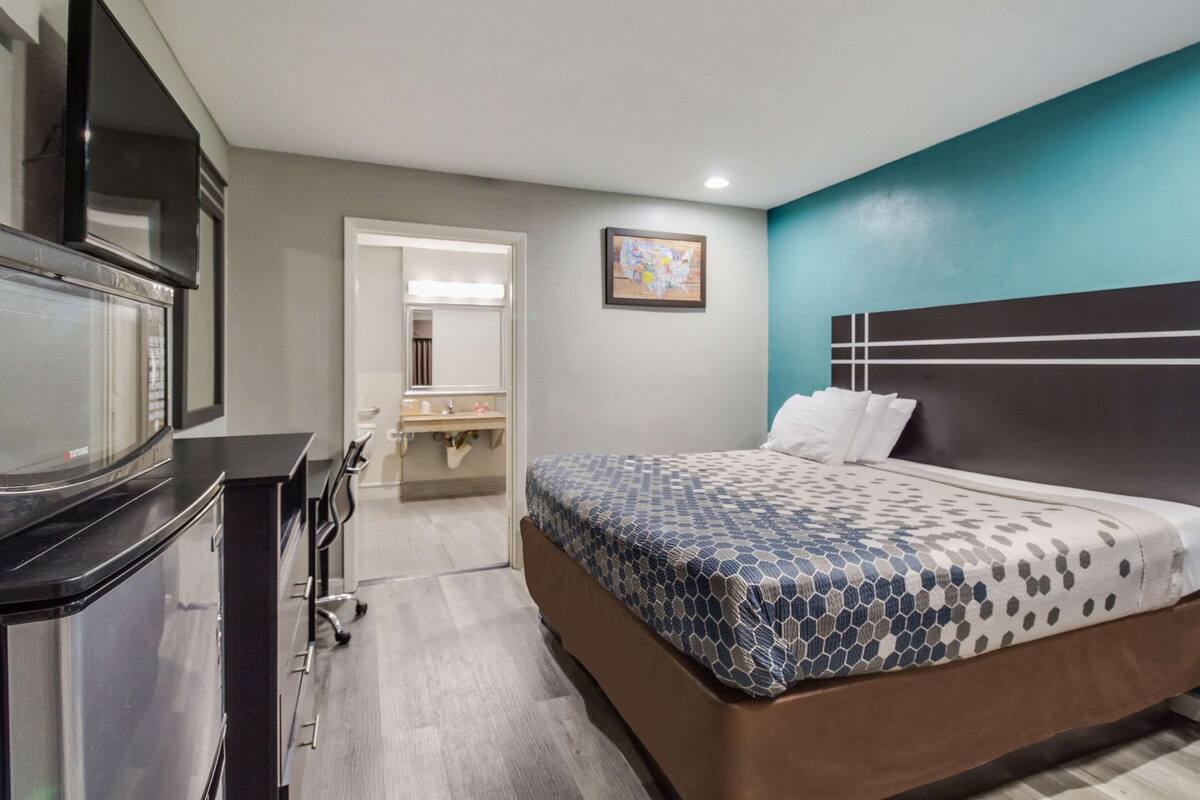 Quarto de hotel com cama, escrivaninha e espelho.