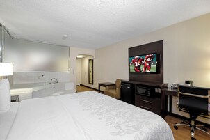 Quarto de hotel com uma cama grande, televisão, escrivaninha e cadeira.