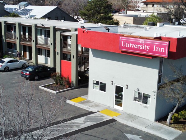 Edifício do University Inn com placa vermelha, estacionamento e escadaria que leva a um andar superior.