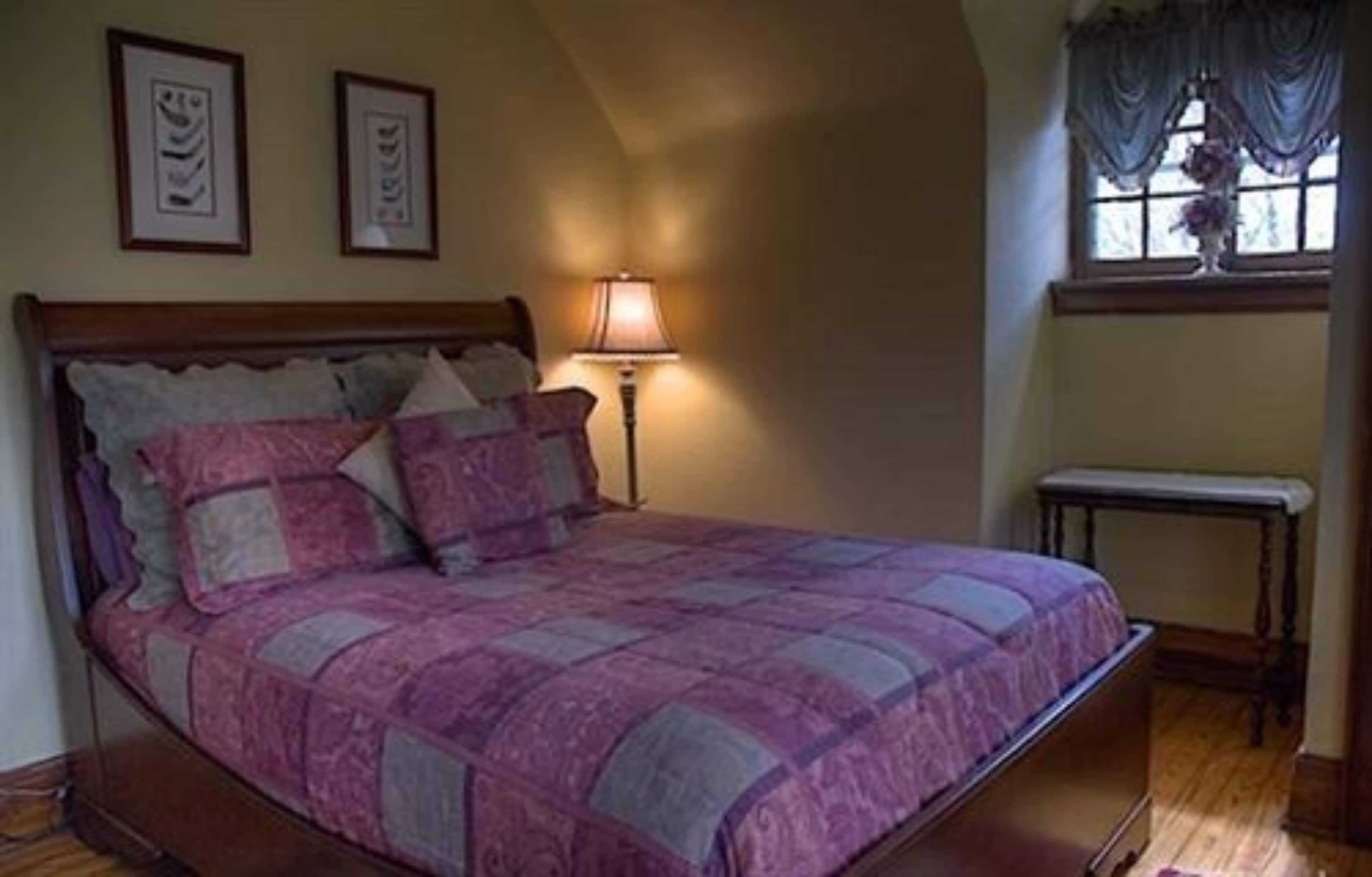 Quarto com uma cama grande, mesa de cabeceira e janela com cortinas.