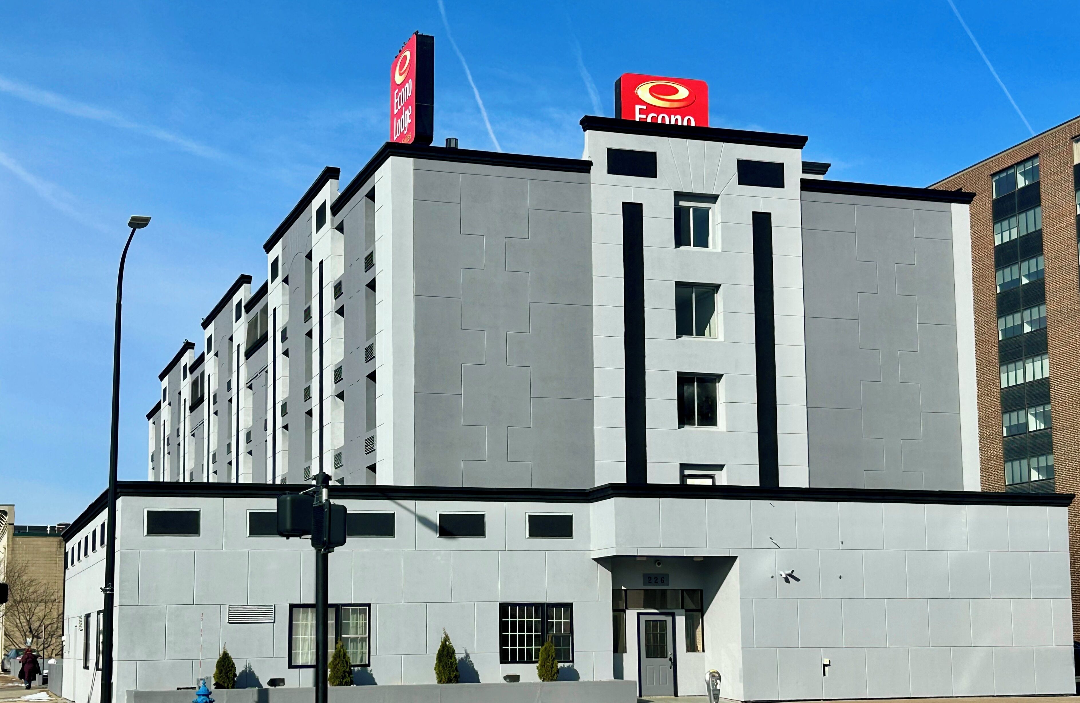 Um hotel moderno com um letreiro Econo Lodge bem visível, fachada plana e um design de janelas em formato de cruz.