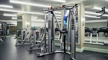 Uma academia com diversos equipamentos de exercício, espelhos e esteiras.