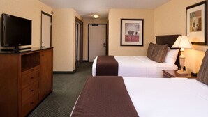 Quarto de hotel com duas camas, televisão, escrivaninha e abajur.