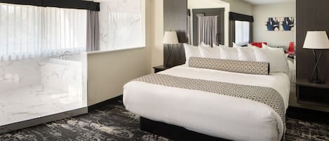 Quarto de hotel com uma cama grande, banheiro com banheira de mármore e vista da cidade.