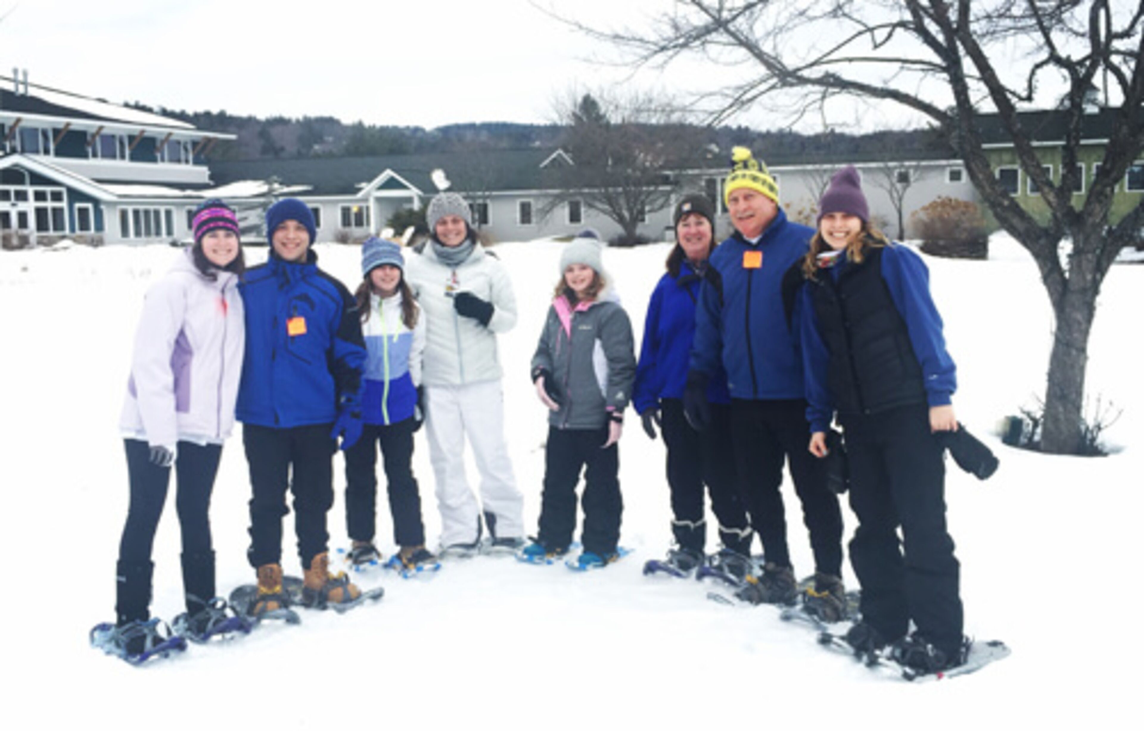 Um grupo de pessoas em pranchas de neve em área externa coberta de neve, com casas ao fundo.
